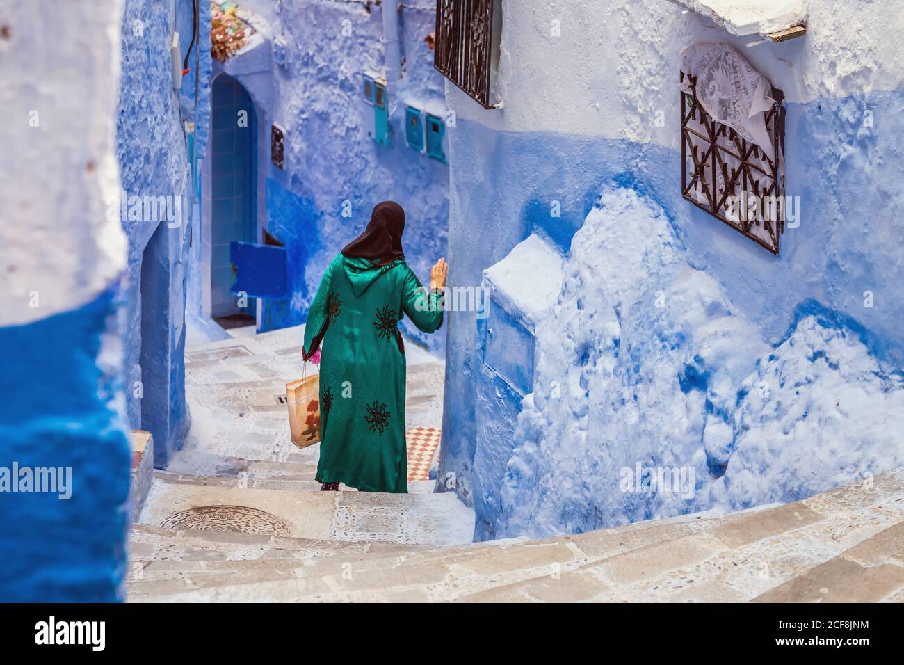 Woman wearing traditional clothes walks in the famous blue city of ...