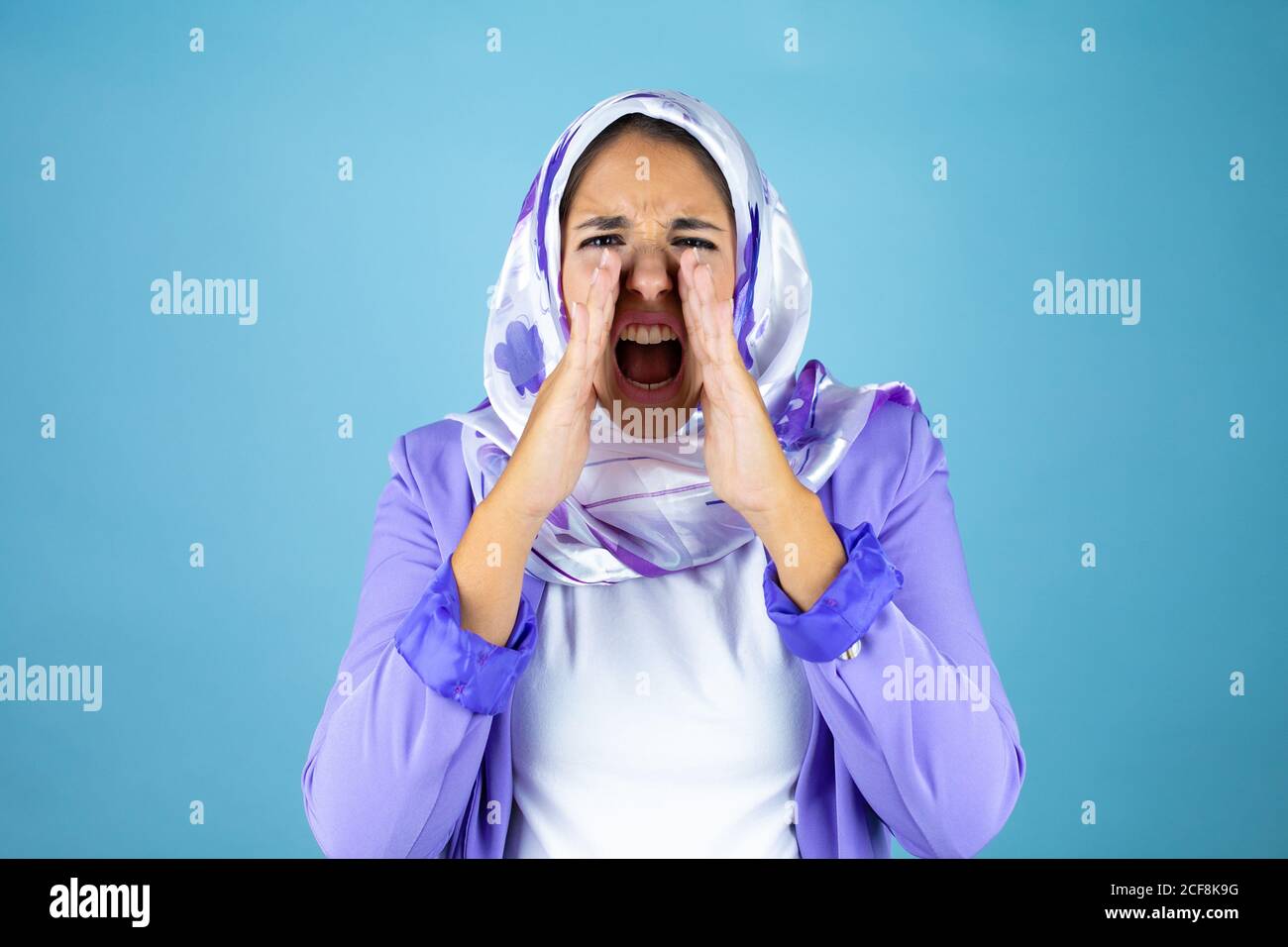Young beautiful arab woman wearing islamic hijab over isolated blue ...