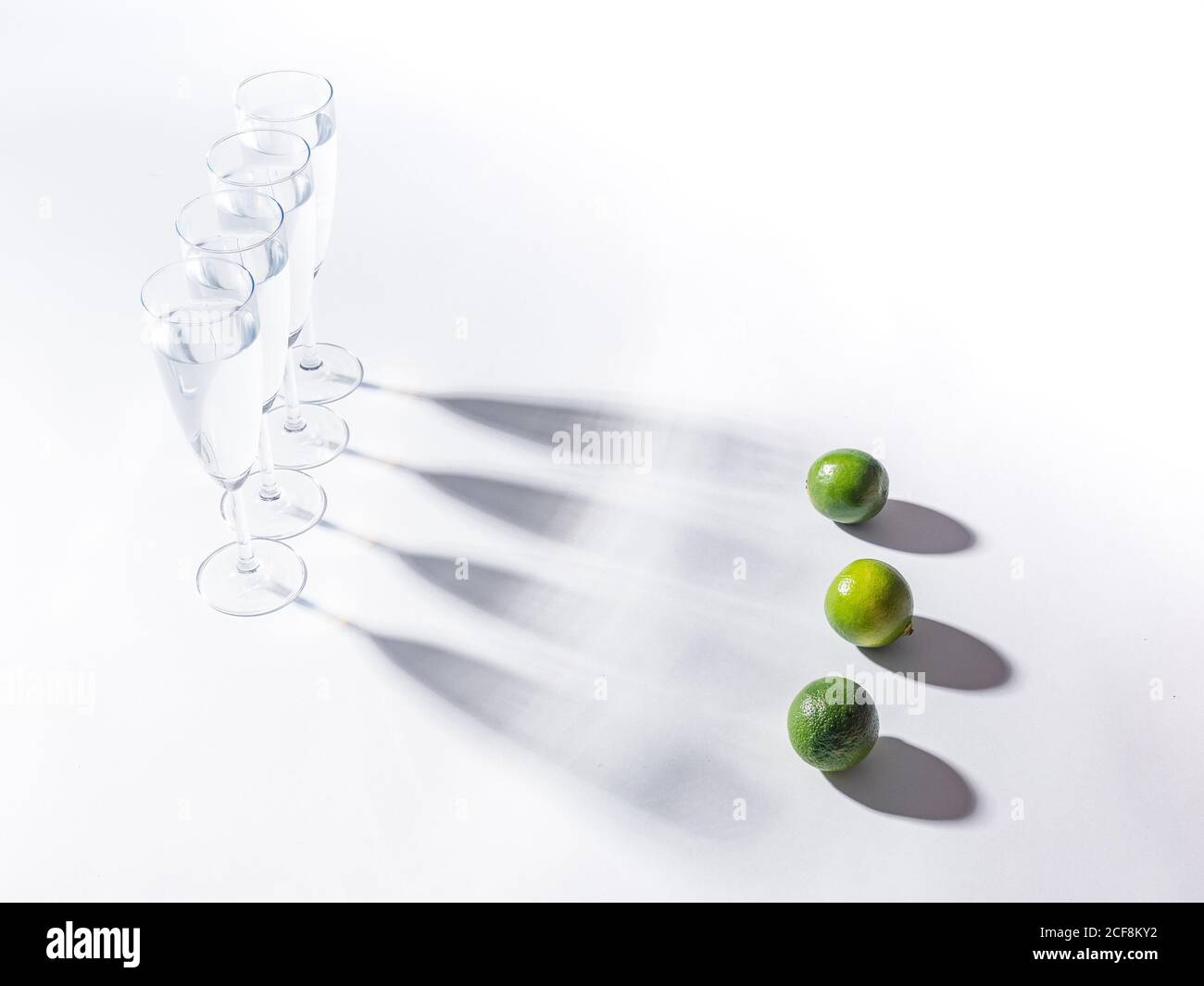 Contrasting shadows from glasses of water and green ripe limes on white ...