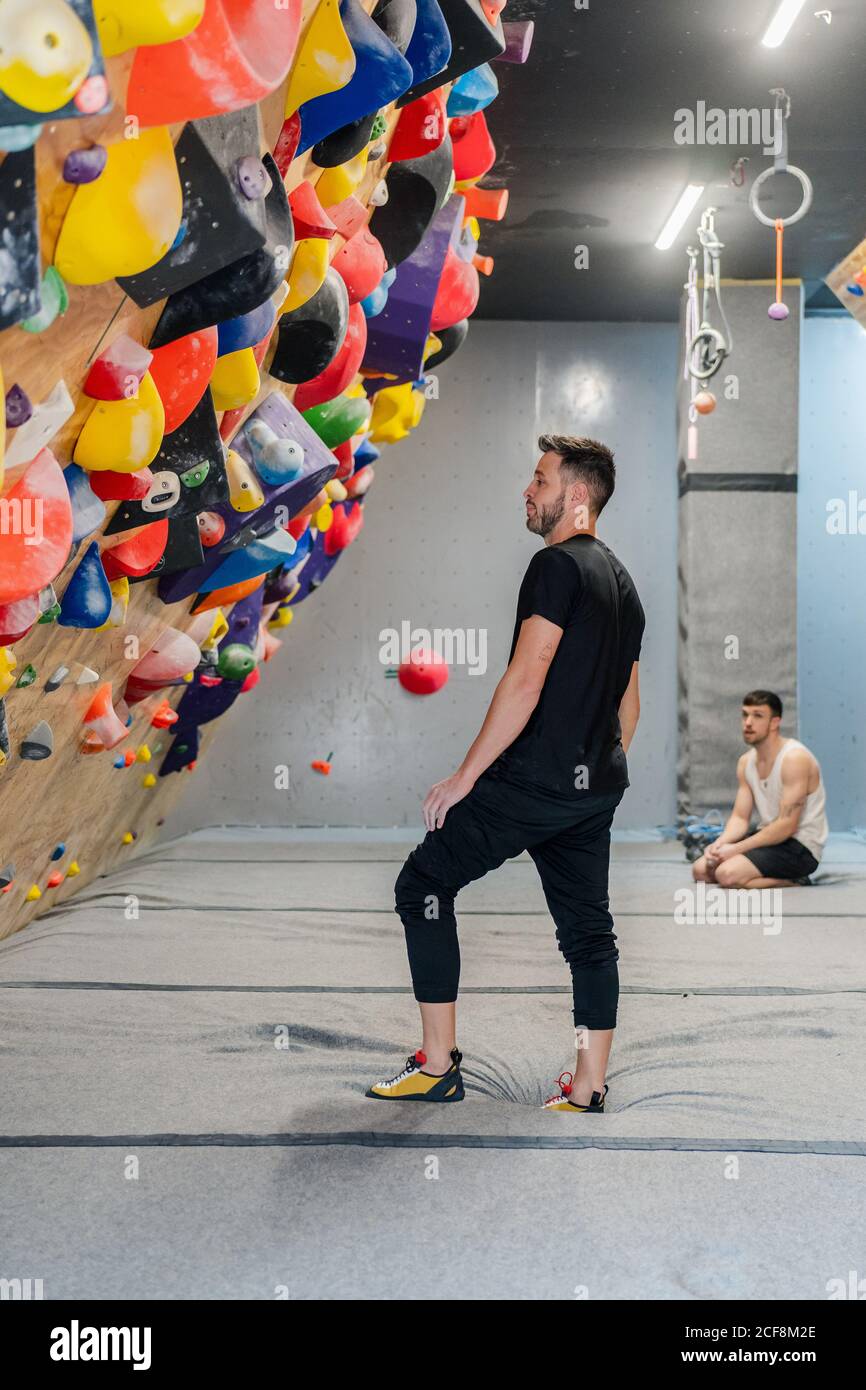 Side view of thoughtful young man in sportswear standing and looking at ...