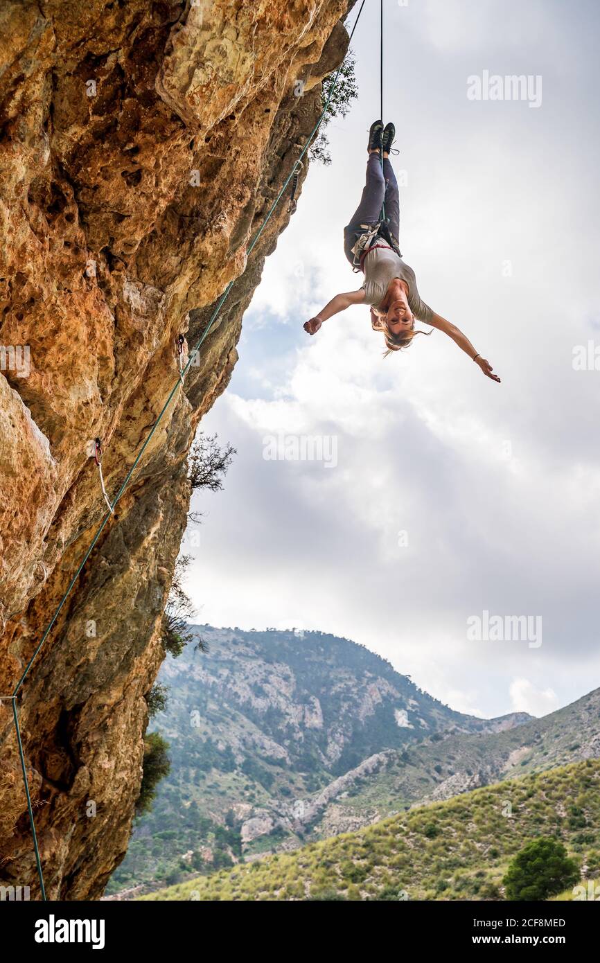 From below fearless young female alpinist enjoying climbing and ...