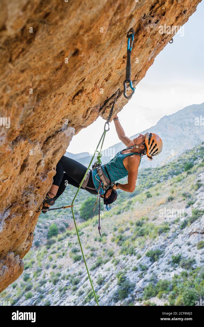 From below side view of active focused youthful female alpinist ...