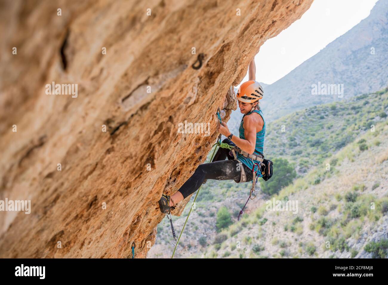 From below side view of active focused youthful female alpinist ...
