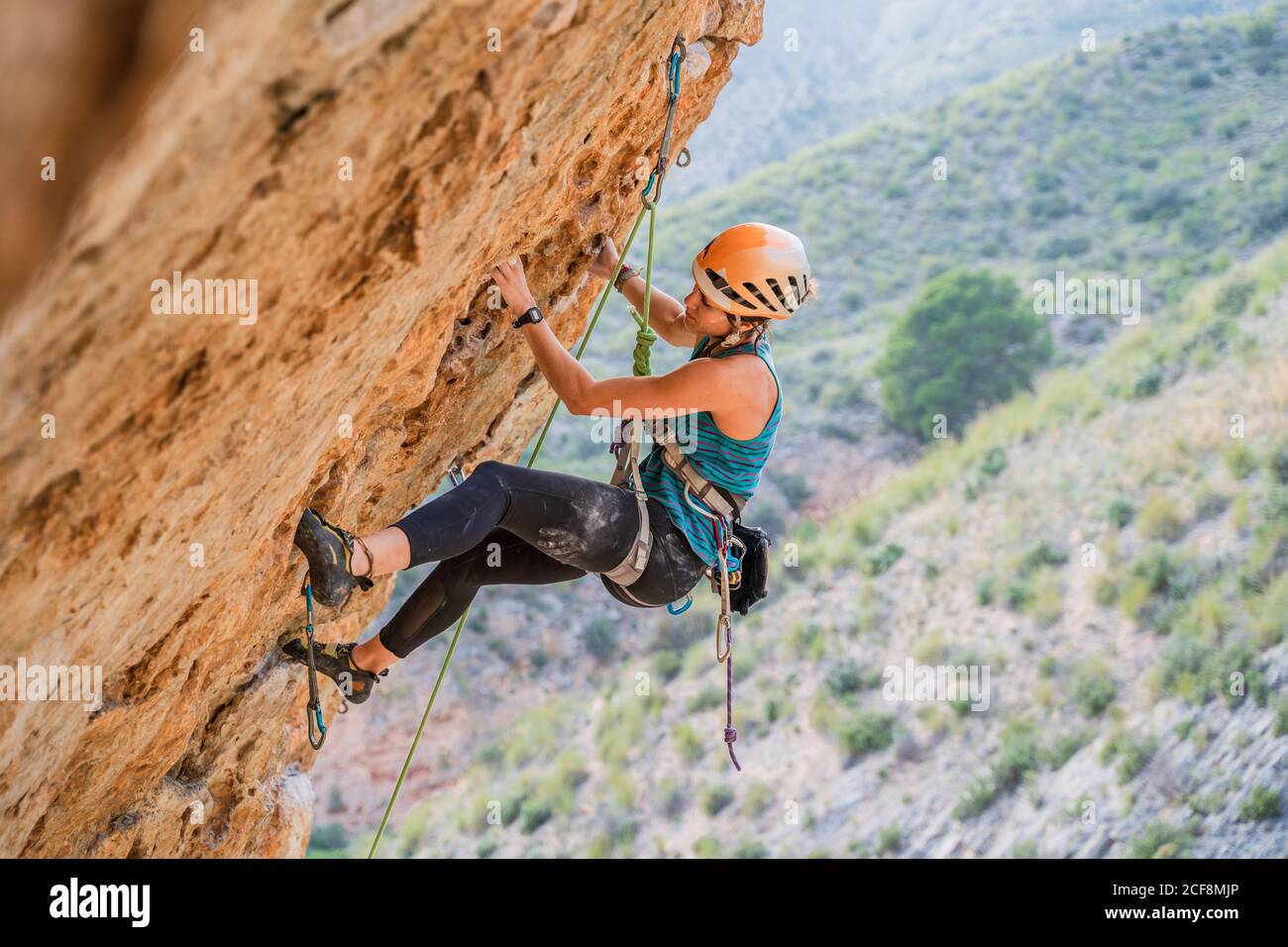From below side view of active focused youthful female alpinist ...
