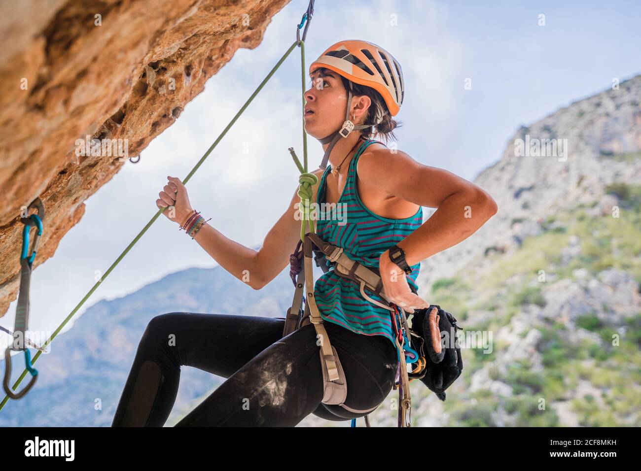 From below side view of active focused youthful female alpinist ...