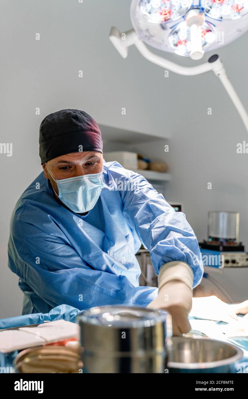 Serious adult man in medical uniform looking away and checking ...