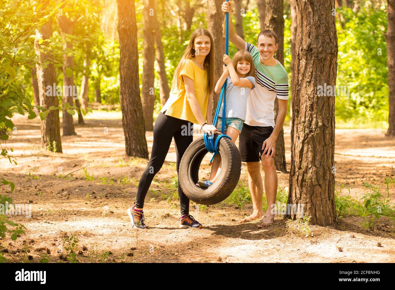 Parents pushing child daughter on tire swing in autumn park Stock Photo ...