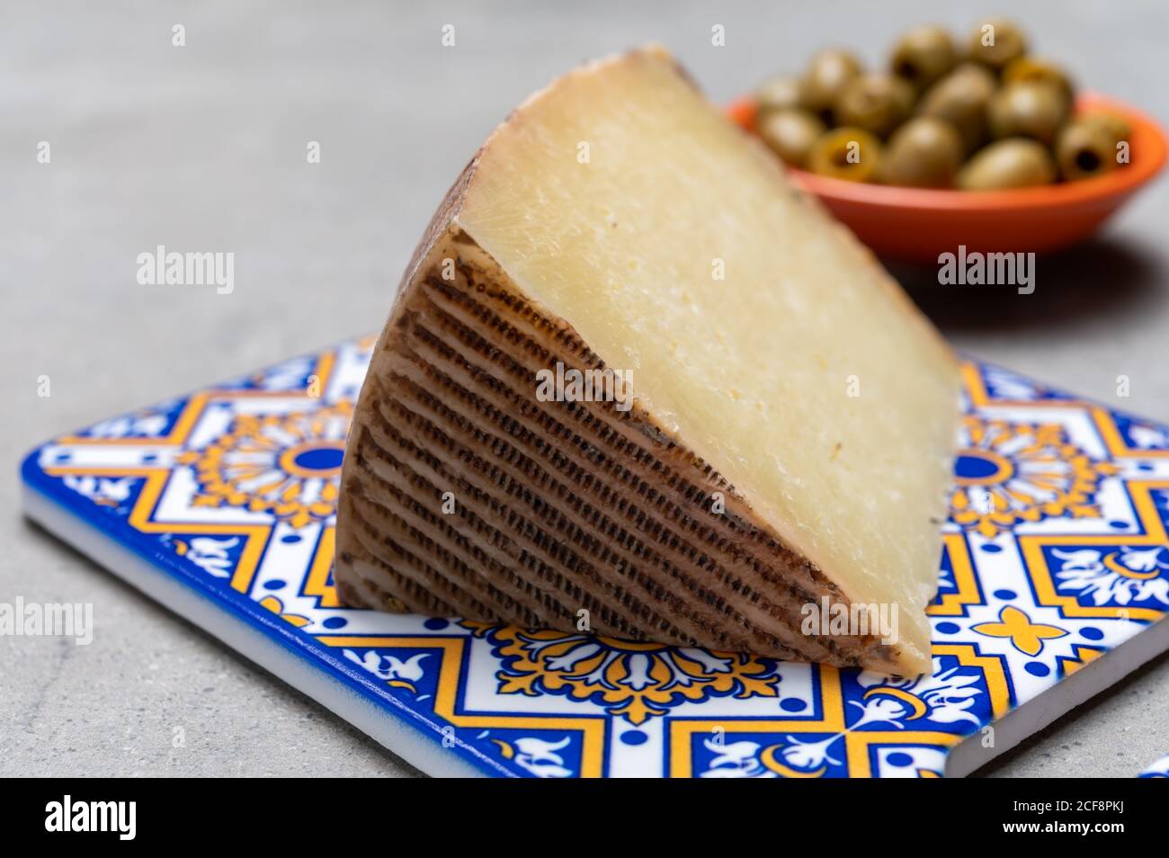 Spanish cheese manchego made from sheep milk with green olives close up ...