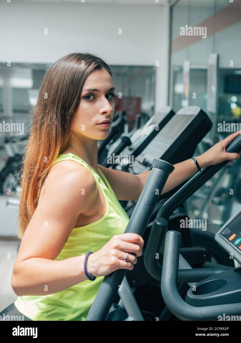 Side view of slim Woman in sportswear training on modern machine in ...