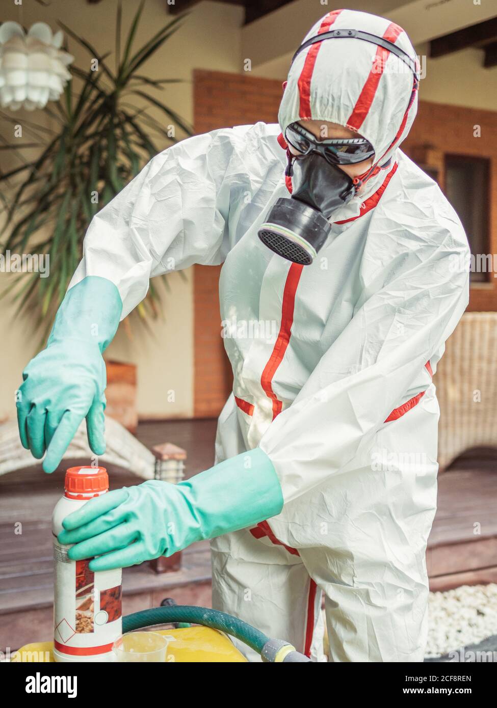 man in suit for fumigation pouring chemical into tank Stock Photo - Alamy