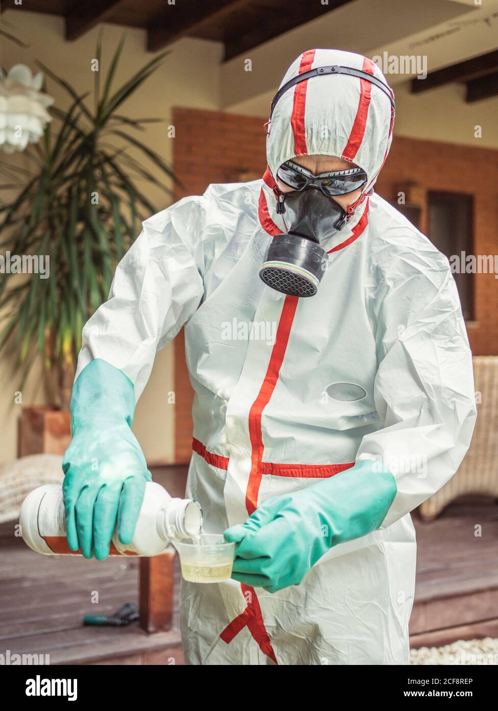man in suit for fumigation pouring chemical into tank Stock Photo - Alamy