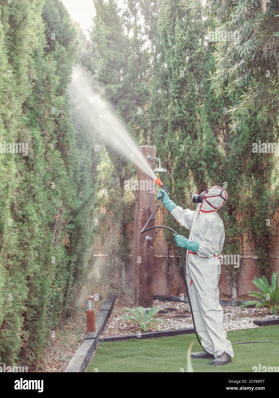 Fumigator in white uniform spraying substance on garden Stock Photo - Alamy