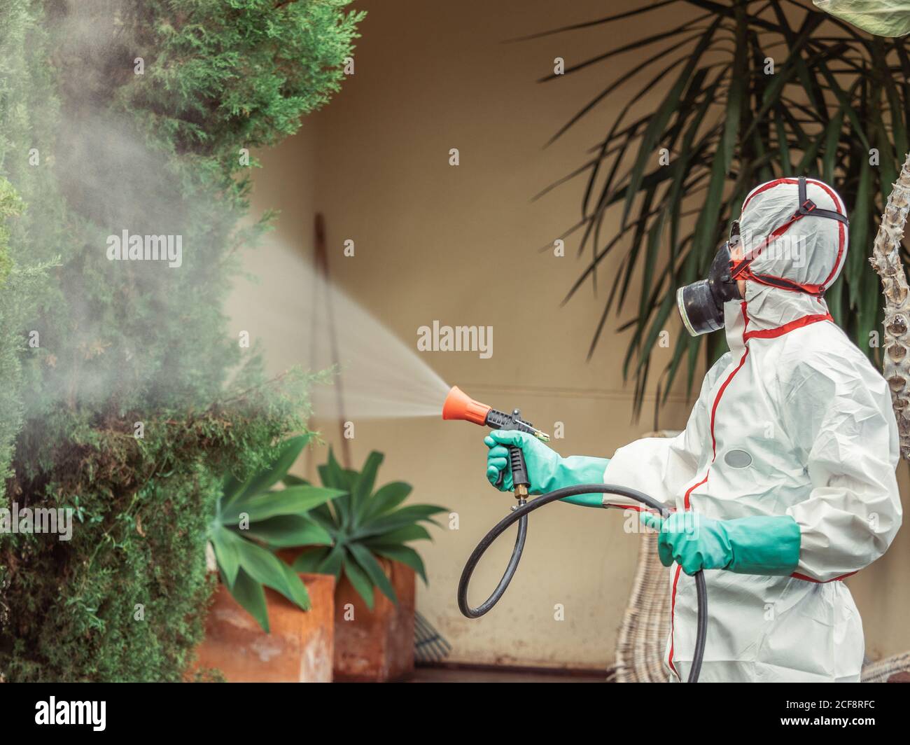 Fumigator in white uniform spraying substance on garden Stock Photo - Alamy