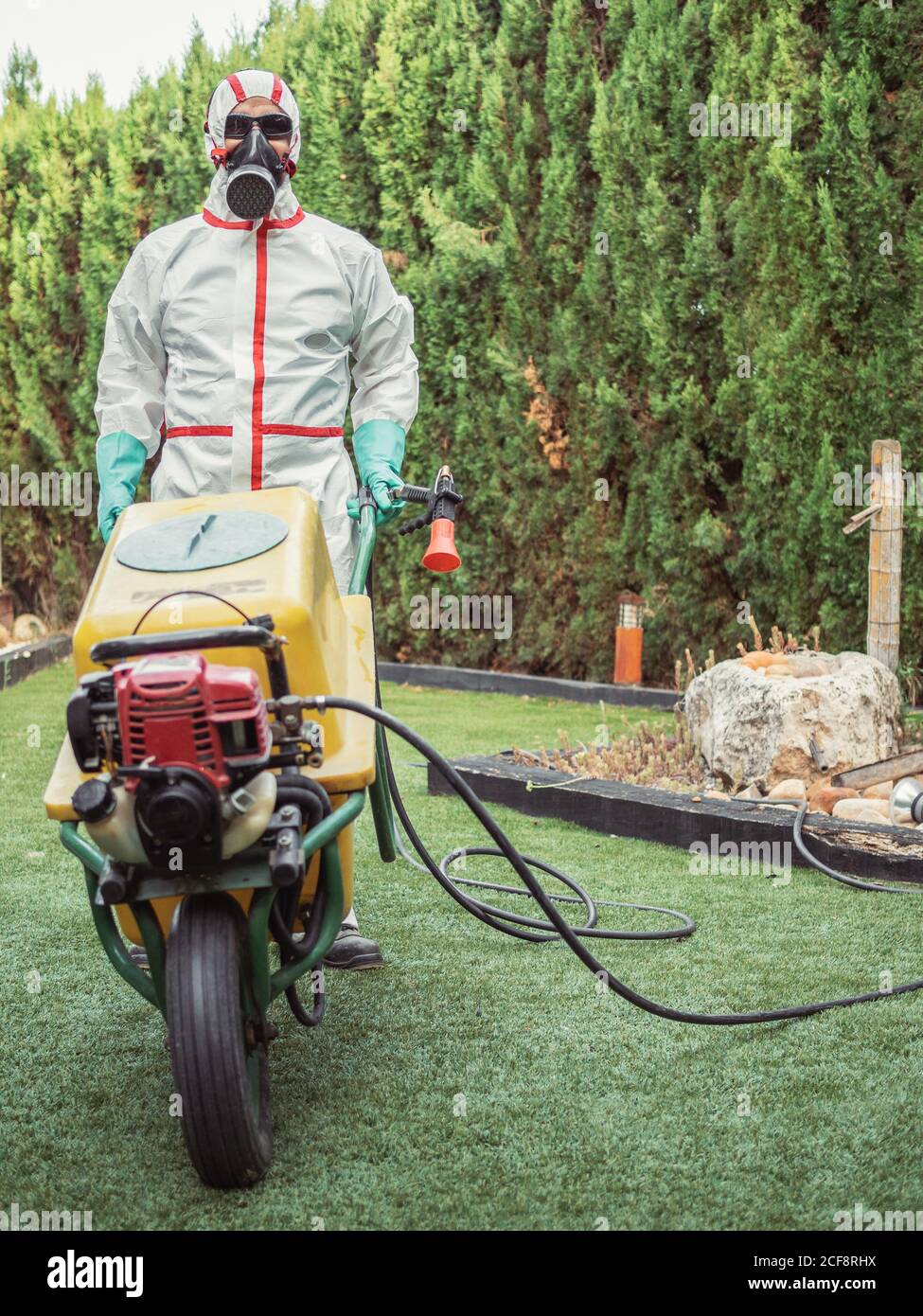 Specialist in uniform for fumigation holding yellow trolley in yard ...