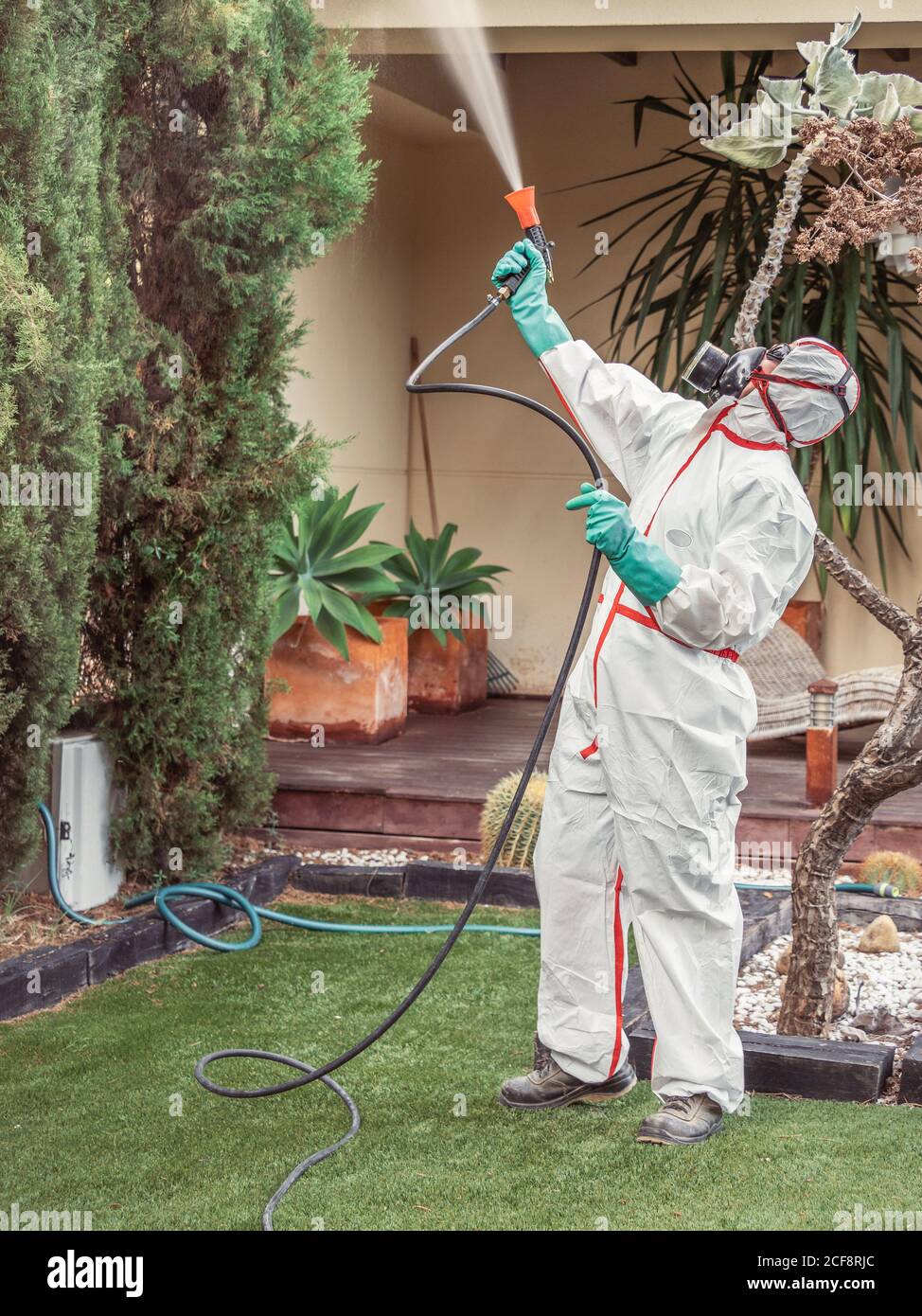 Fumigator in white uniform spraying substance on garden Stock Photo - Alamy