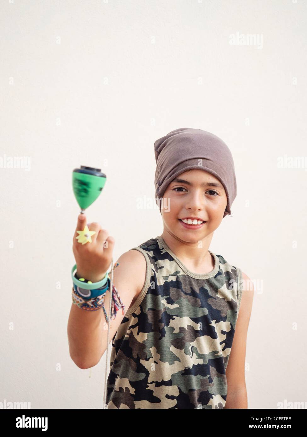 Smart stylish boy in hat easily spinning green top while looking at ...