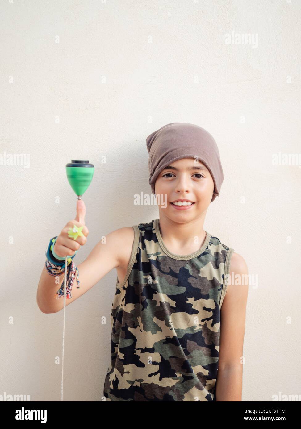 Smart stylish boy in hat easily spinning green top while looking at ...