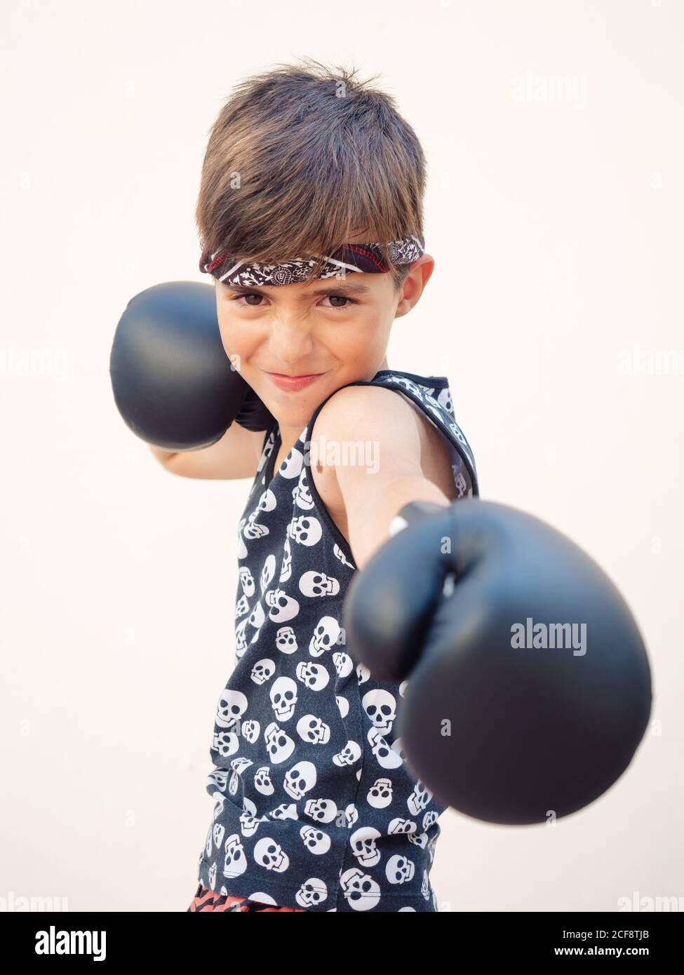 Happy energetic concentrated boy in black boxing gloves beating punch ...