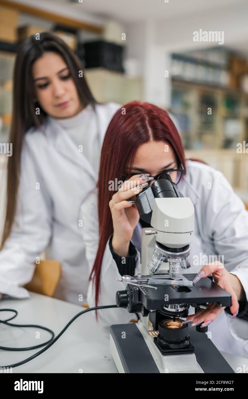 Woman using microscope near colleagues in laboratory Stock Photo - Alamy