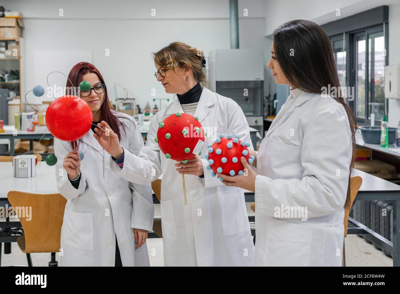 Mature Woman in lab coat examining molecule models of young female ...