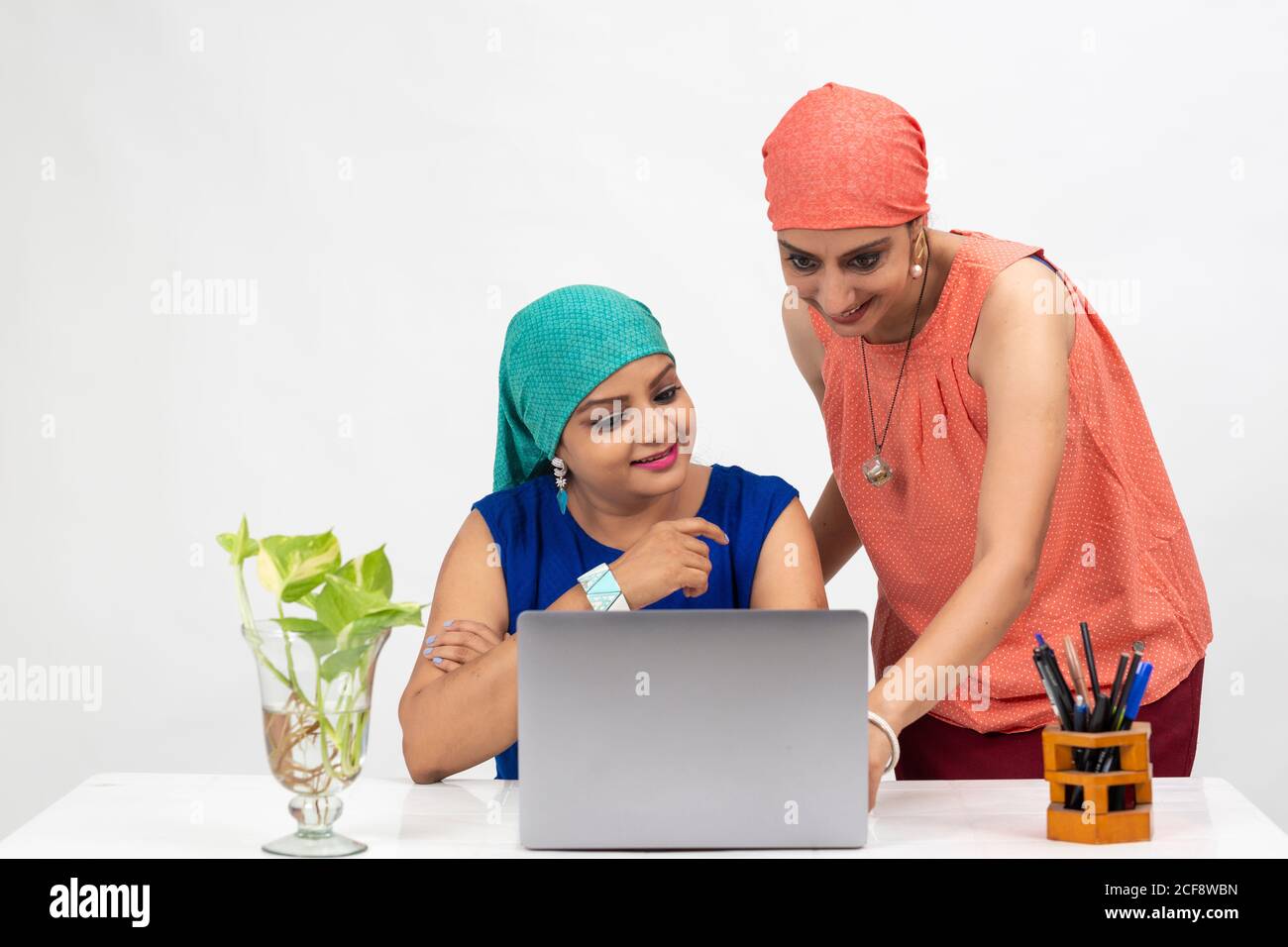 Two smiling Indian women at the table, distance learning for students ...