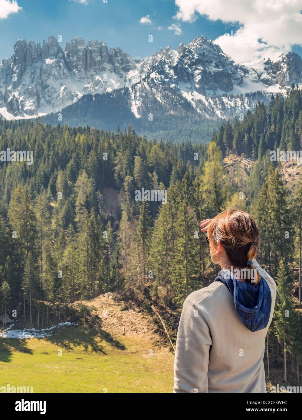 Back view of young Woman in sweater protecting face from sun by hand ...