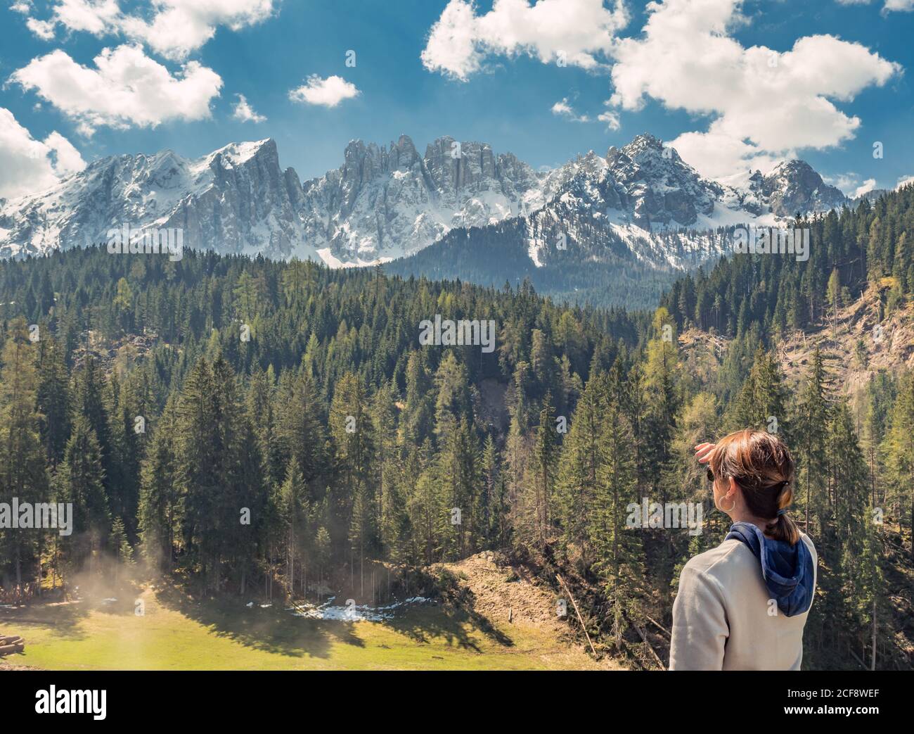 Back view of young Woman in sweater protecting face from sun by hand ...