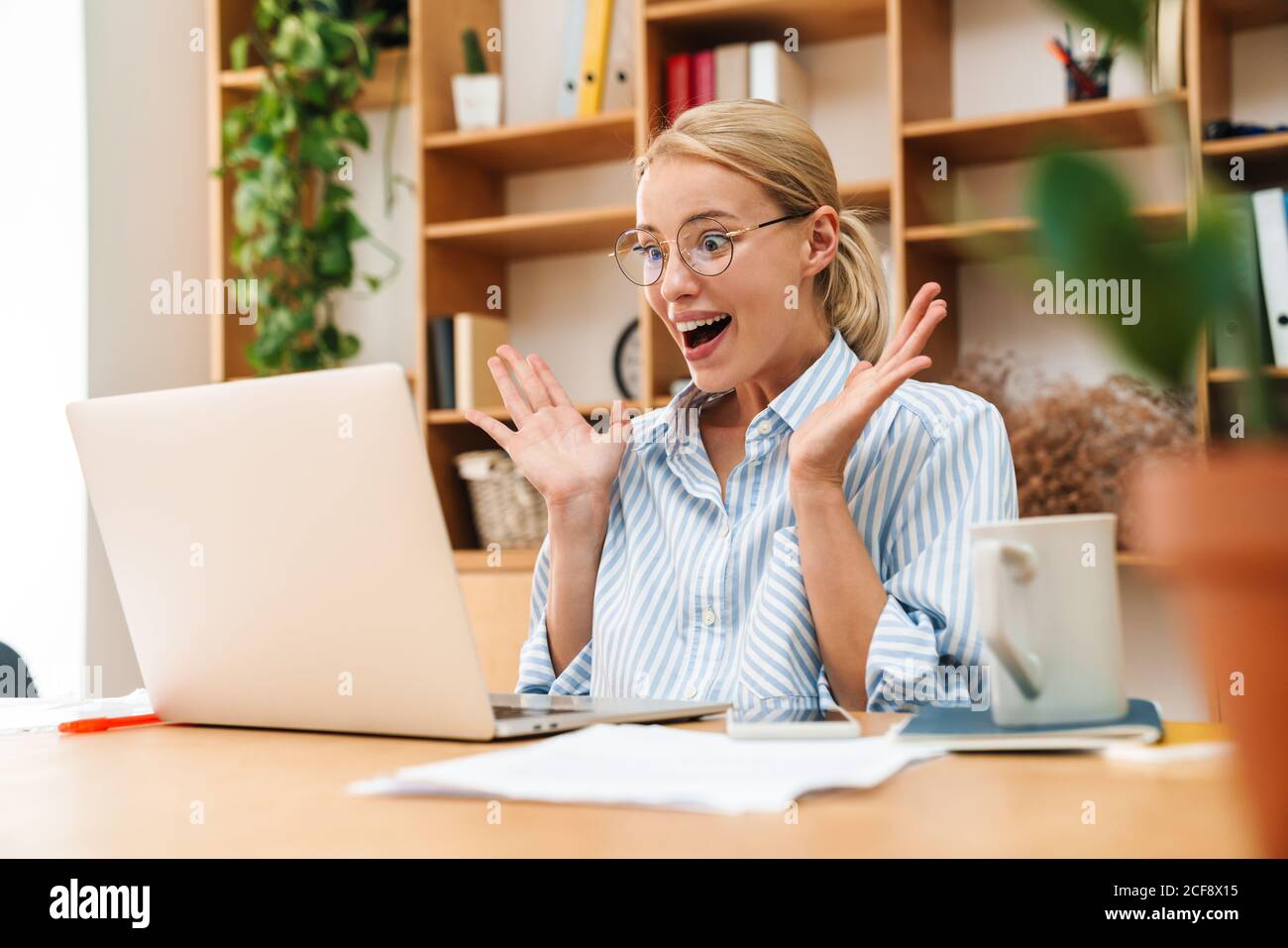 Image of excited young businesswoman expressing surprise while working ...