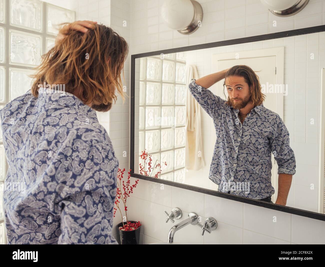 Handsome male checking hairstyle in mirror reflection Stock Photo - Alamy