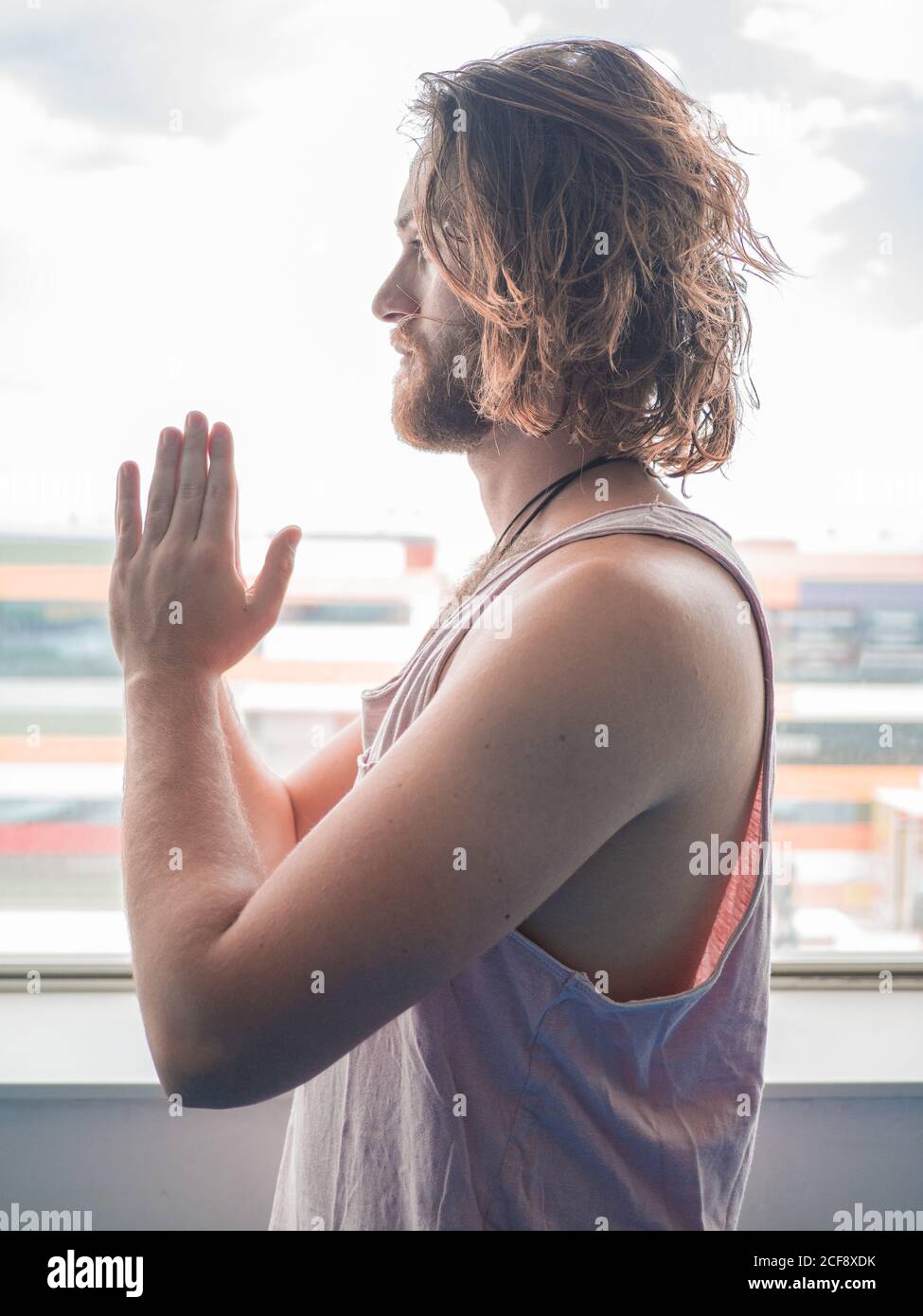 Bearded man in sportswear standing in one leg with prayer hands looking ...