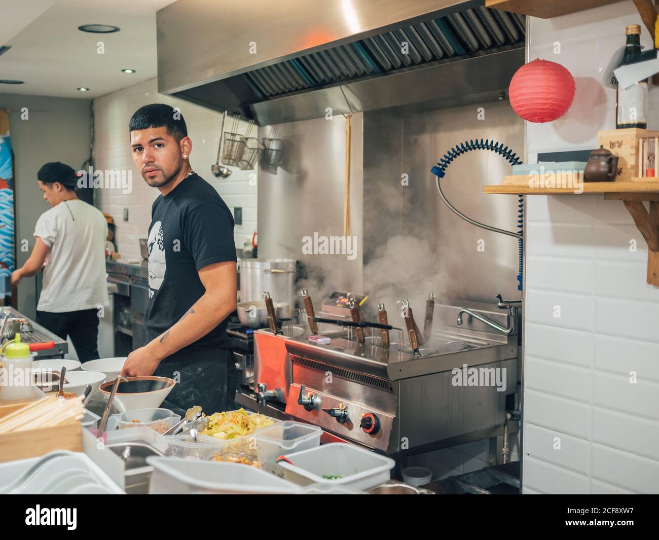 Handsome ethnic man standing in kitchen and choosing ingredients for ...