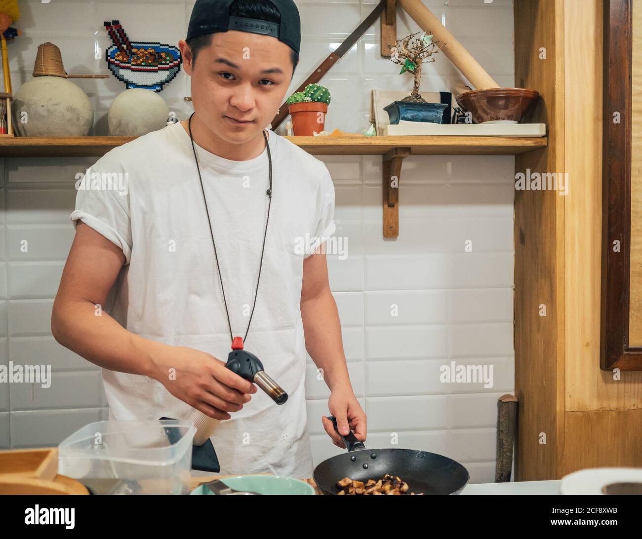 Concentrated young man frying ingredients for Japanese dish called ...