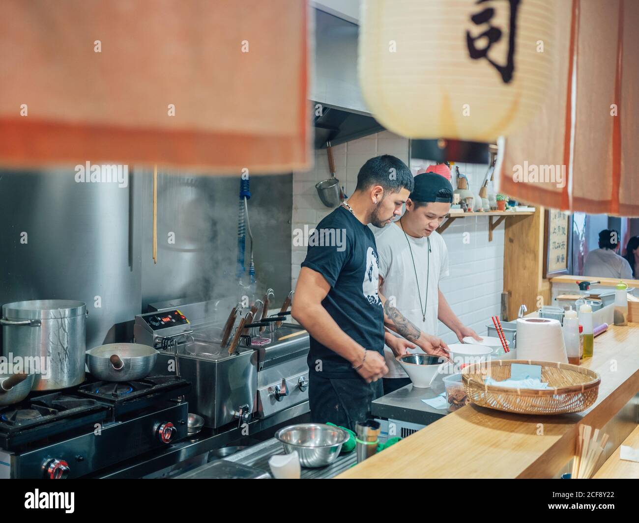 From above kitchen with young men cooking Japanese dish ramen in ...