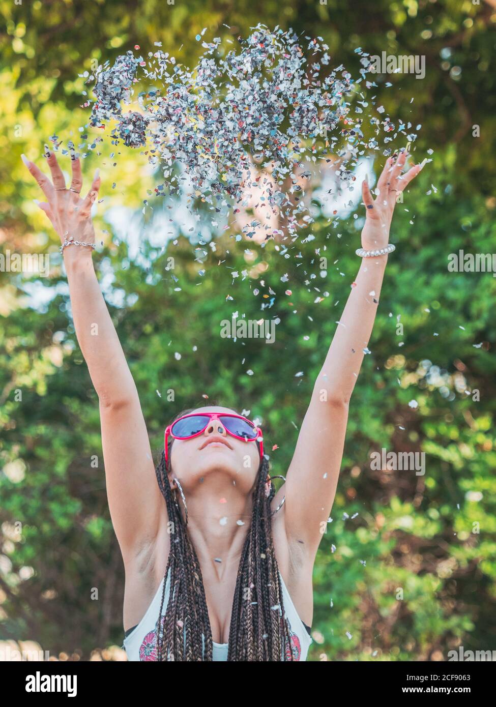Joyful young female with dreadlocks sitting on ground legs crossed ...