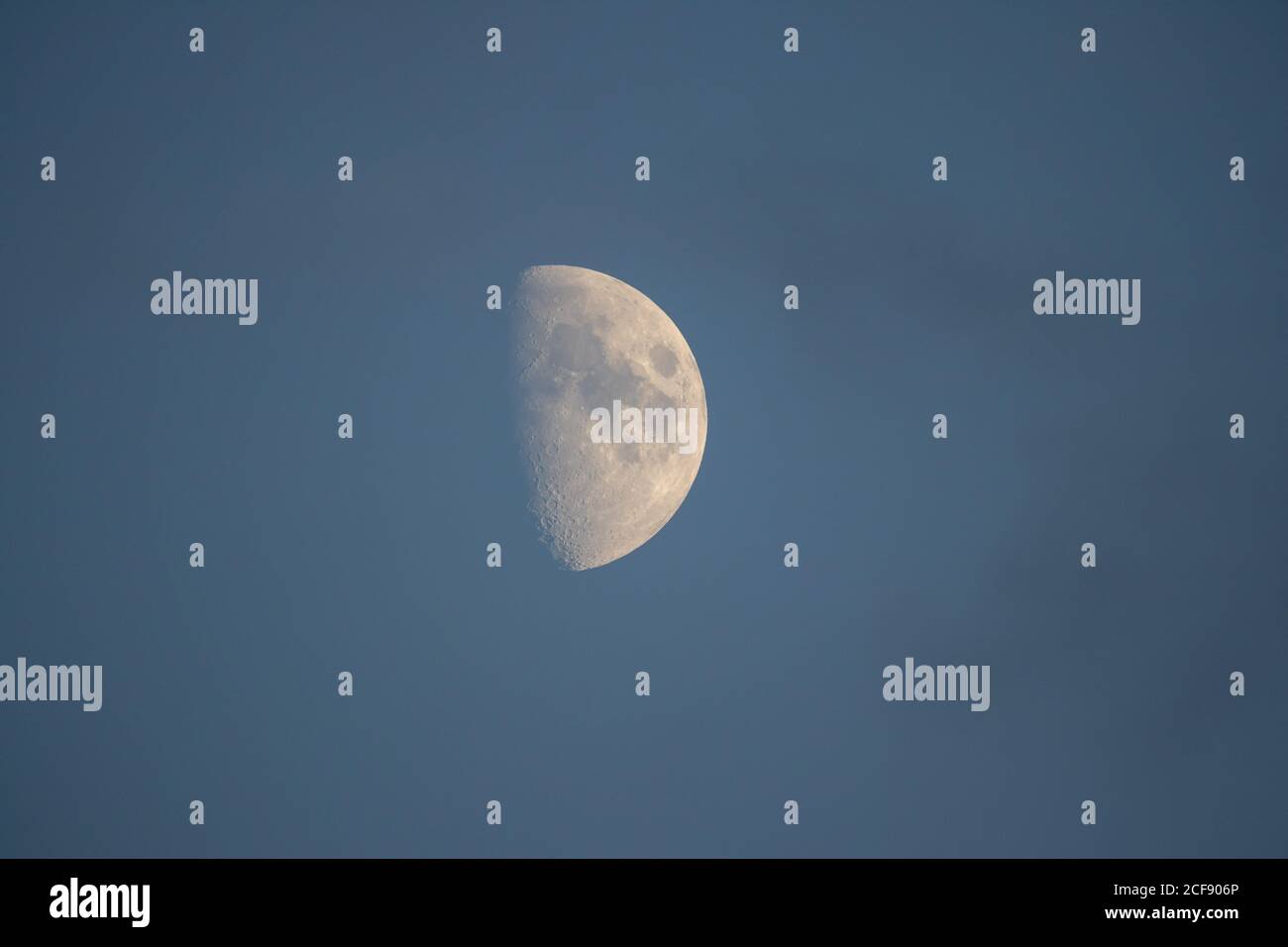 A half moon shining white in the blue of the late evening sky Stock ...