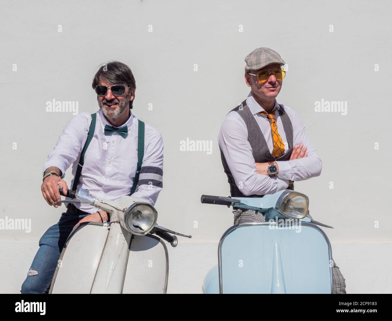 Positive middle-aged hipsters in elegant clothes with retro motorbikes ...