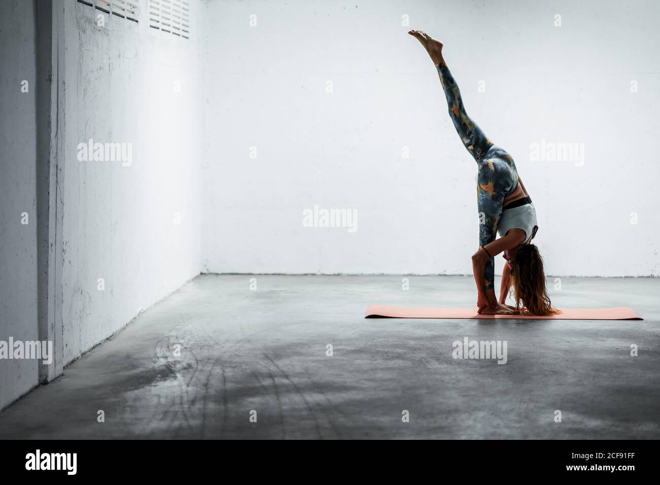 Side view of flexible female in active wear standing on mat and doing ...