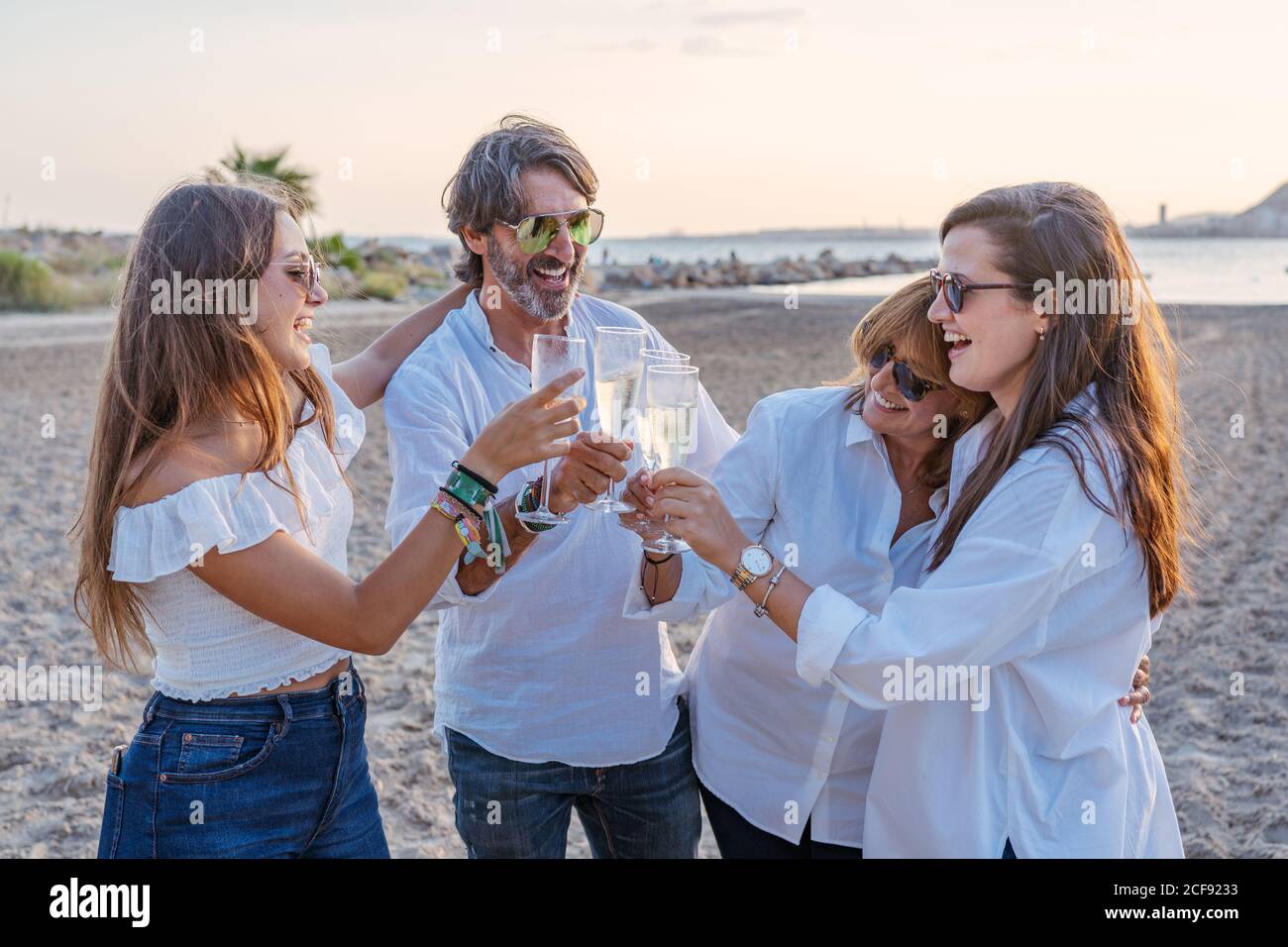 Cheerful mature parents and young daughters clinking glasses of wine ...