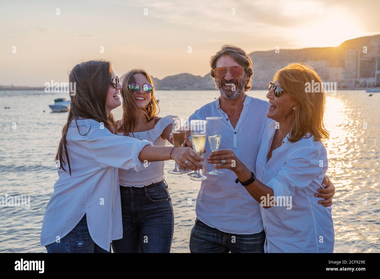 Cheerful mature parents and young daughters clinking glasses of wine ...