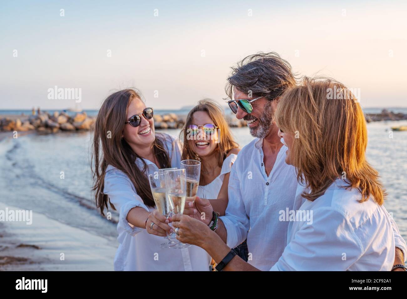 Cheerful mature parents and young daughters clinking glasses of wine ...