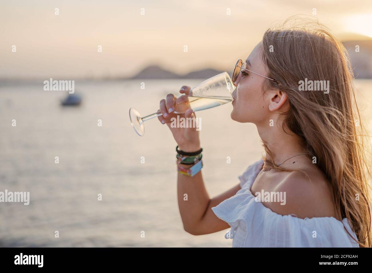 Side view of happy young female with closed eyes drinking wine while ...