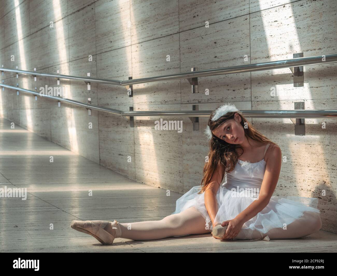 Ballerina sitting on floor stretching graceful leg in classroom Stock ...