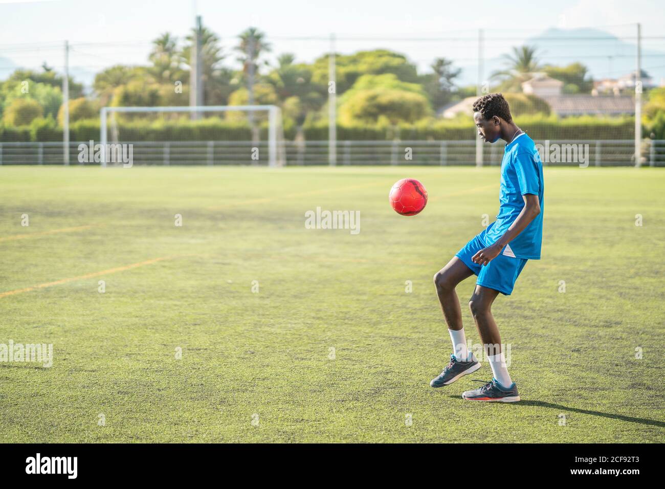 Ethnic teenager juggling football ball Stock Photo - Alamy