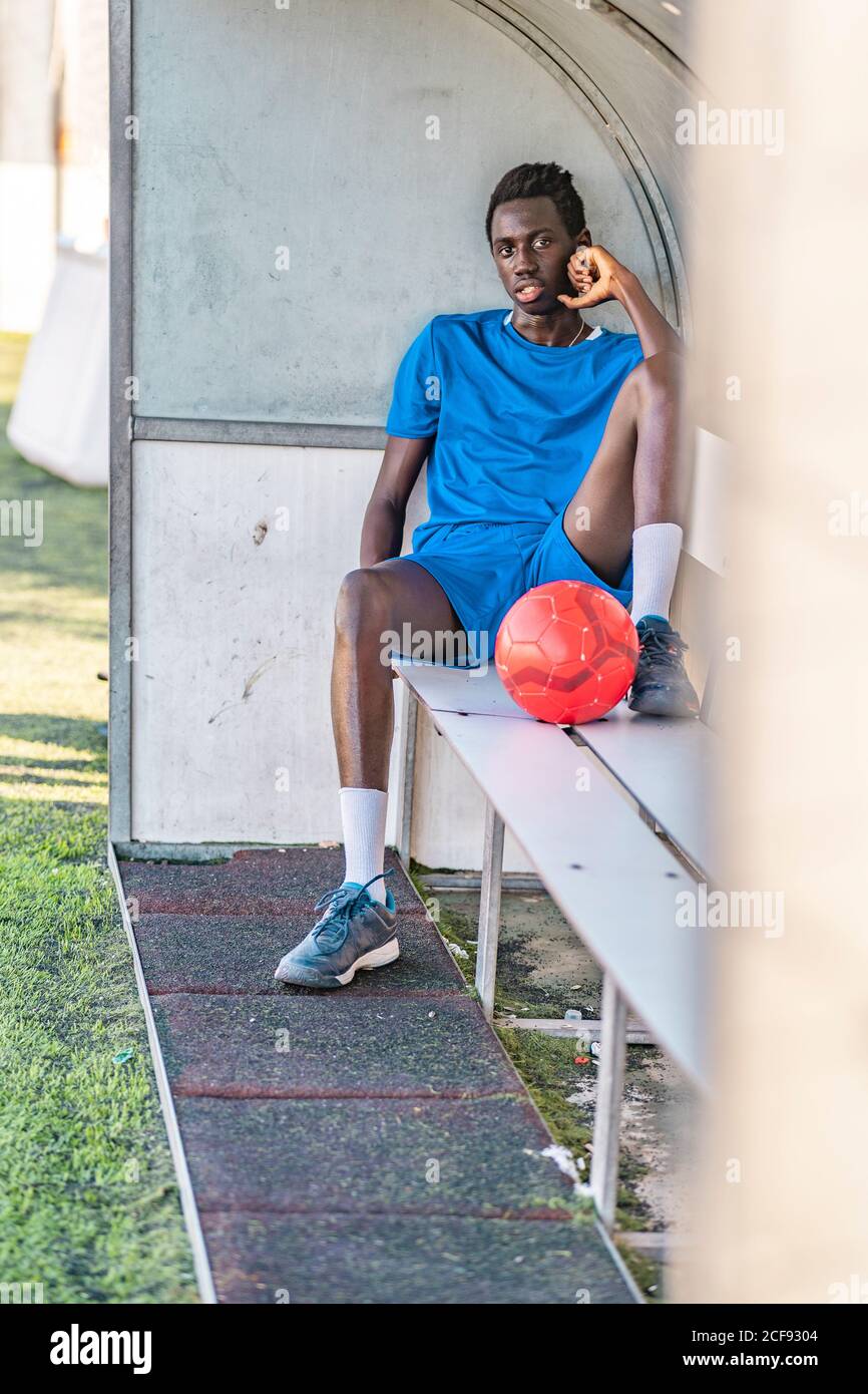 Black football player resting on bench Stock Photo - Alamy