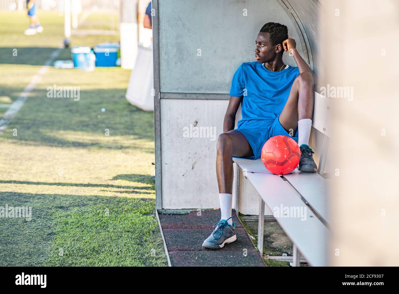 Black football player resting on bench Stock Photo - Alamy