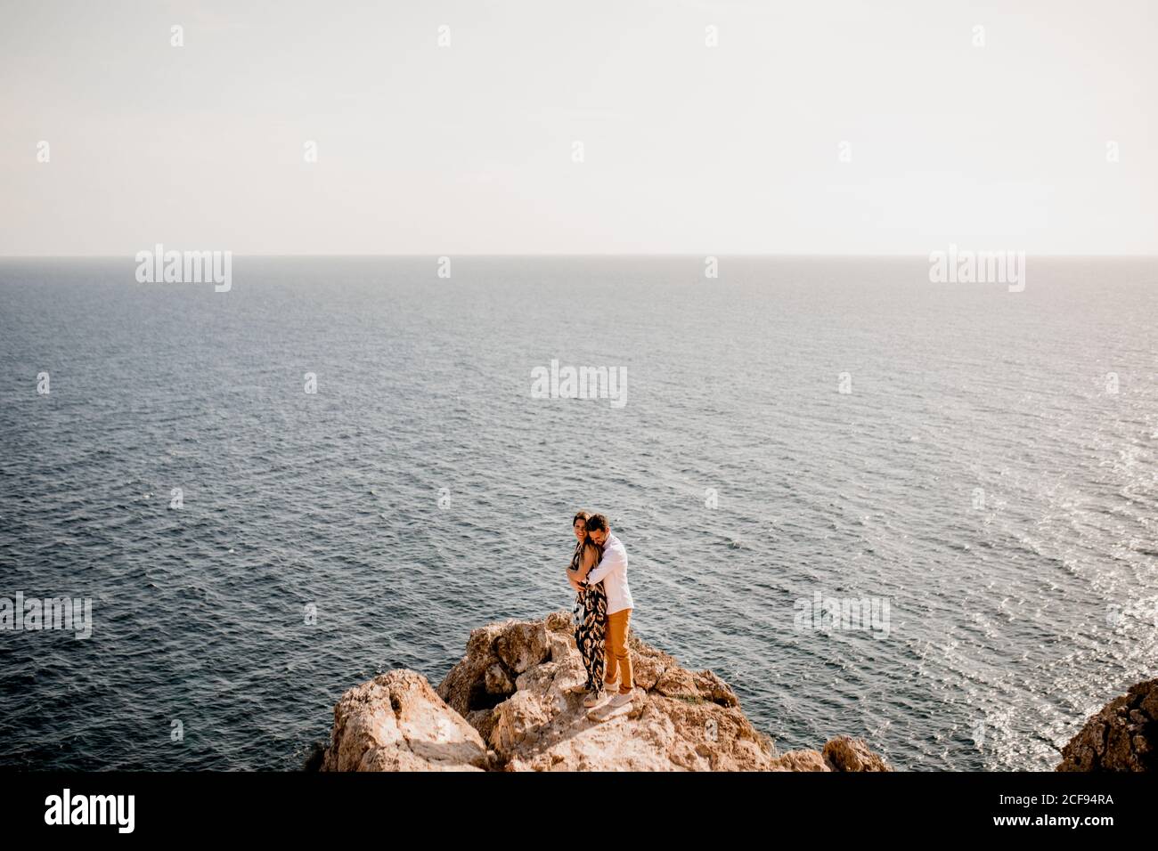 From above peaceful Woman and man hugging on stone cliff above endless ...