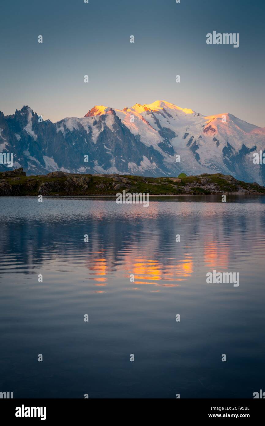 Amazing landscape of hilly shore and lake reflecting sunset in sky and ...