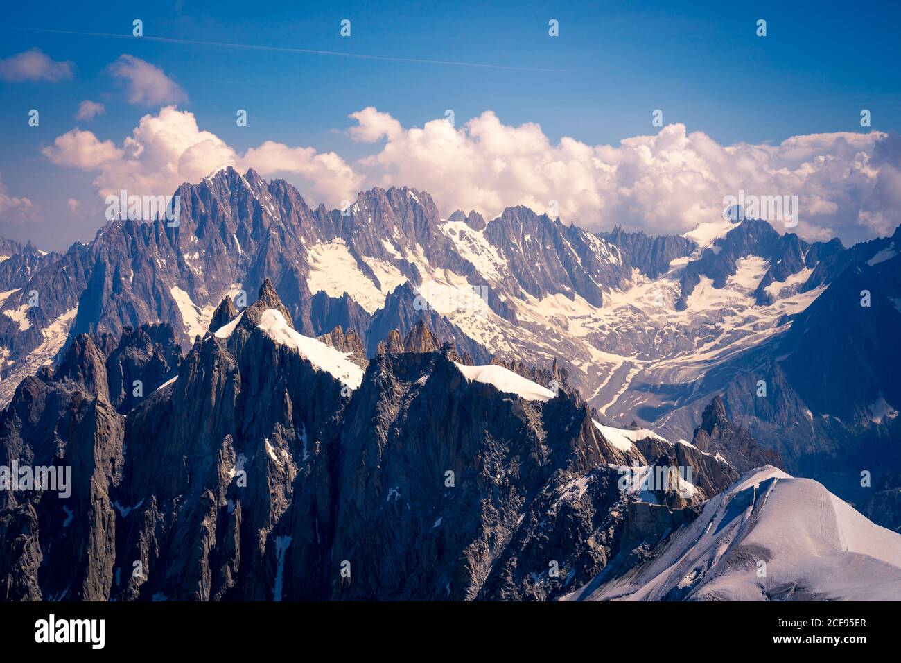 White sharp mountain peaks in snow raising up to cloudy sky Stock Photo ...