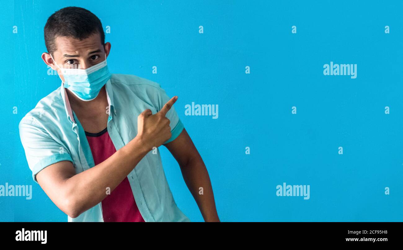 Male in a protective face mask pointing to his left with a finger ...