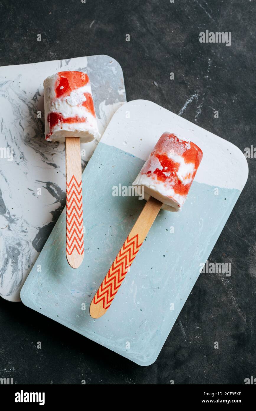 Top view of two watermelon and cream popsicles laying on fancy dishes ...